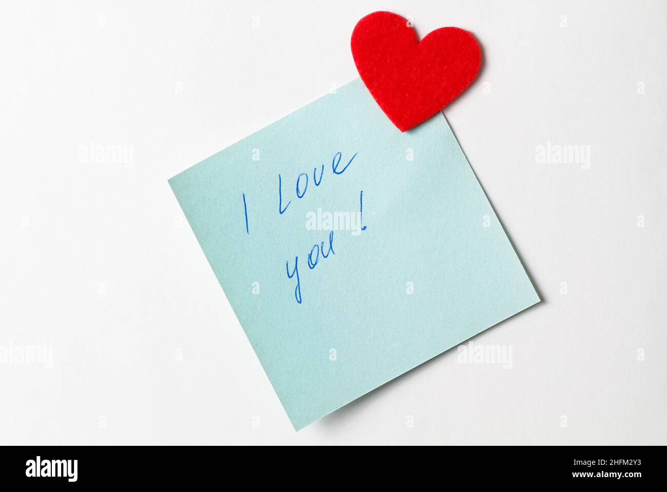 A close up of a blue sticky note with the word I Love You with red ...