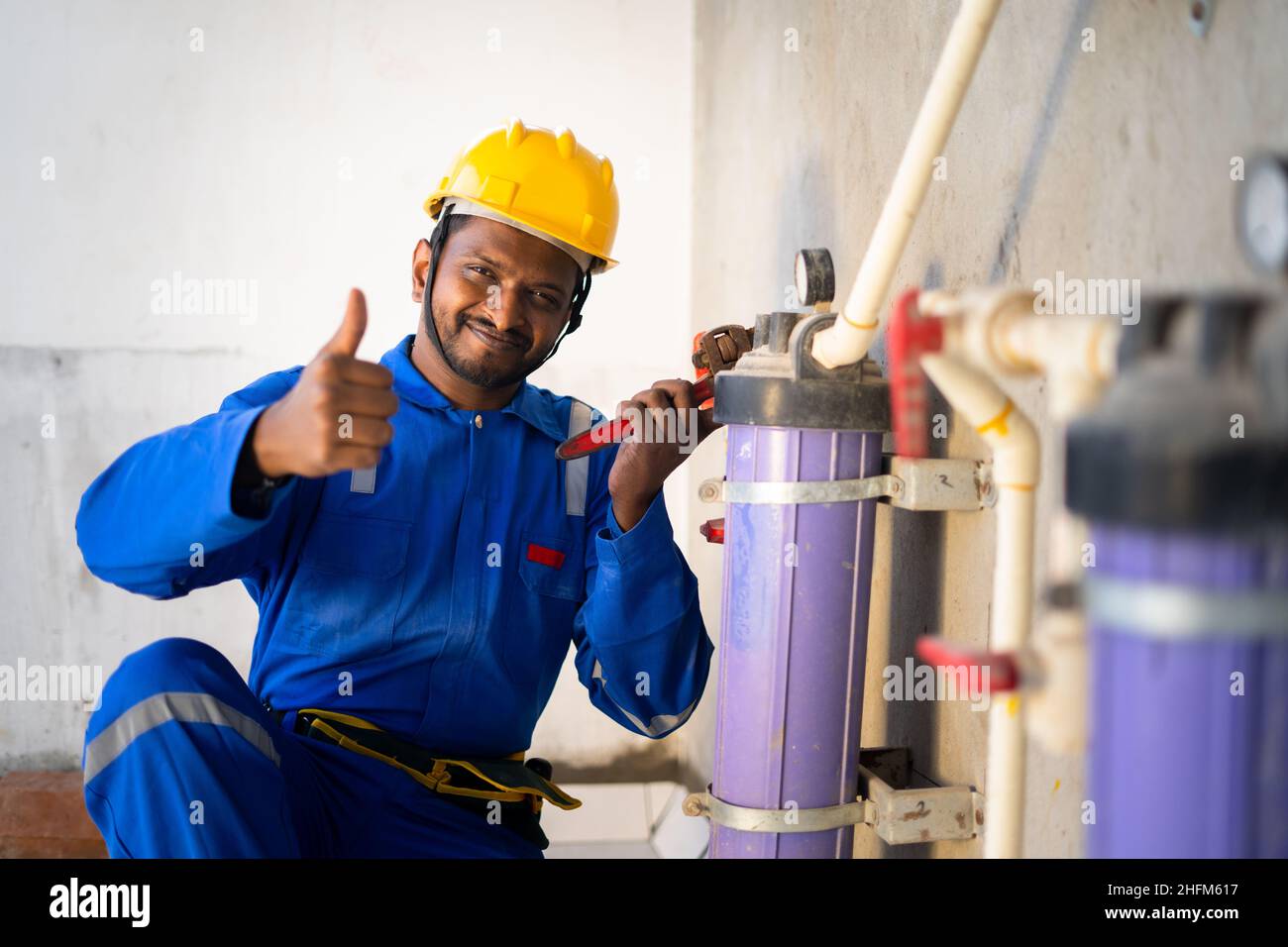 smilling young indian engineer or repairman showing thumbs up sign or ...