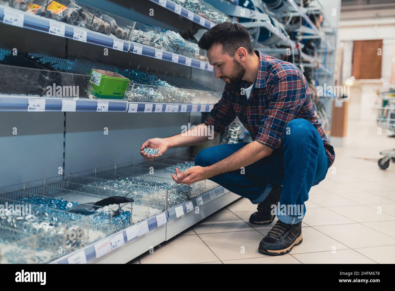 a customer in a hardware store chooses self-tapping screws, screws and ...