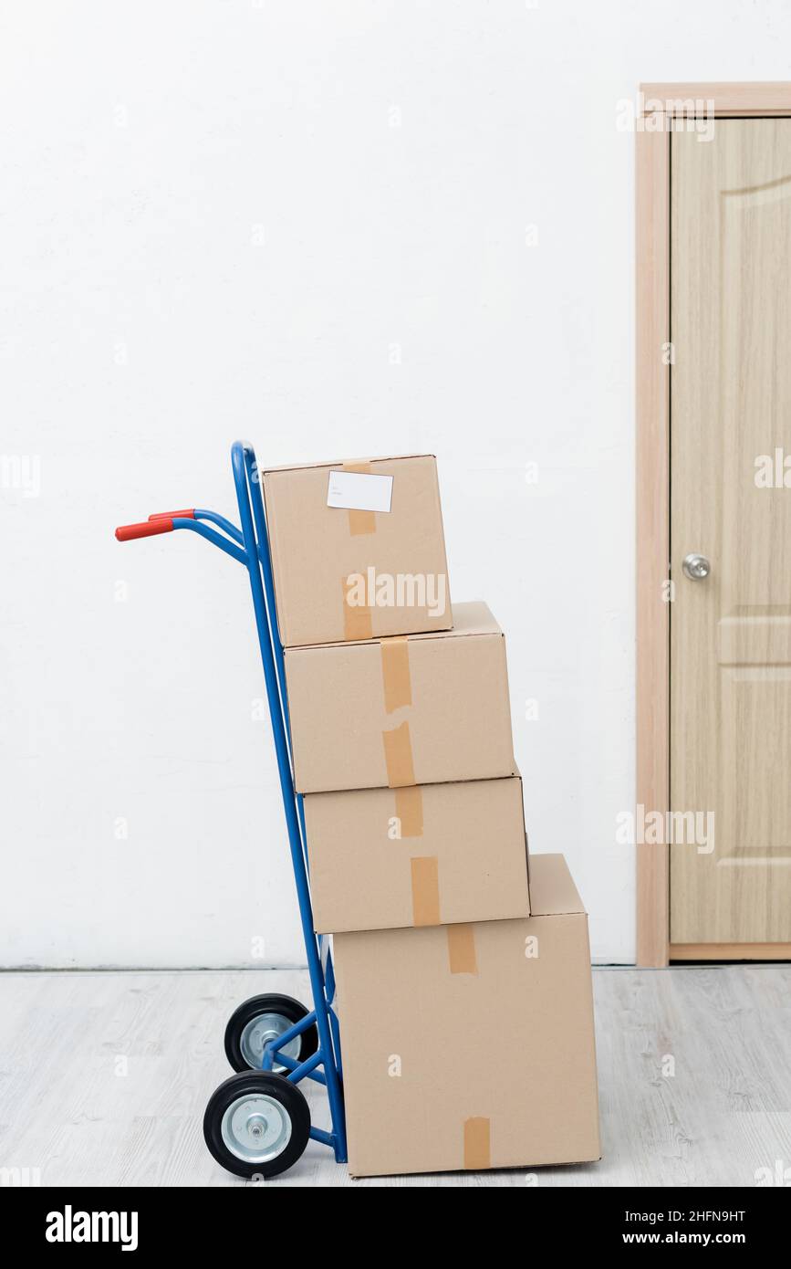 Cardboard boxes on cart near door in hallway Stock Photo - Alamy