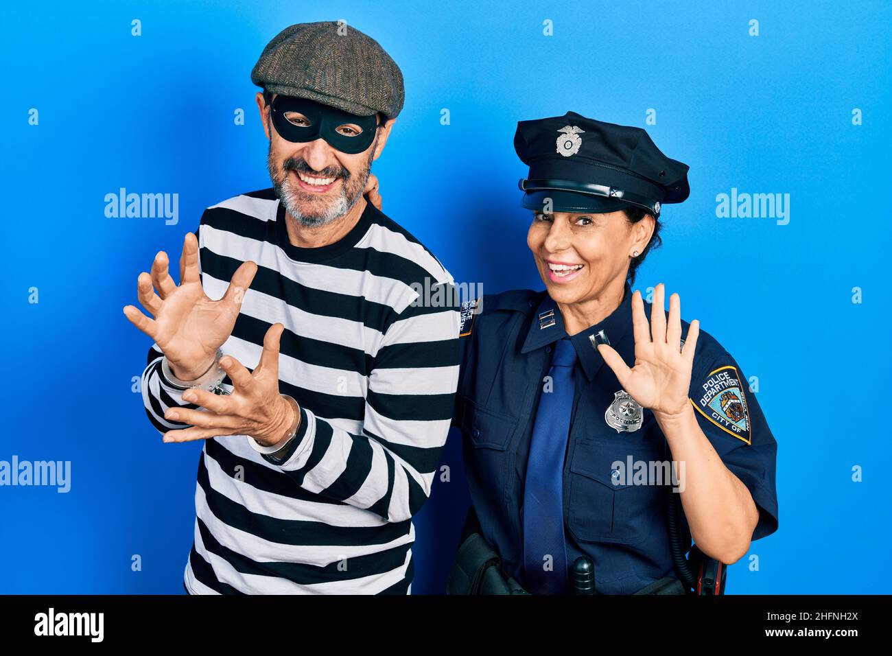 Middle age couple of hispanic woman and man wearing thief and police ...