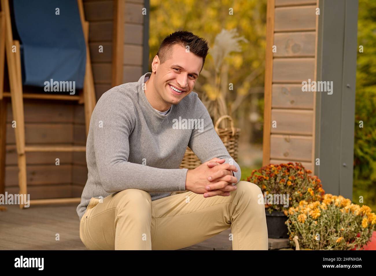 Man sitting near house looking at camera Stock Photo - Alamy