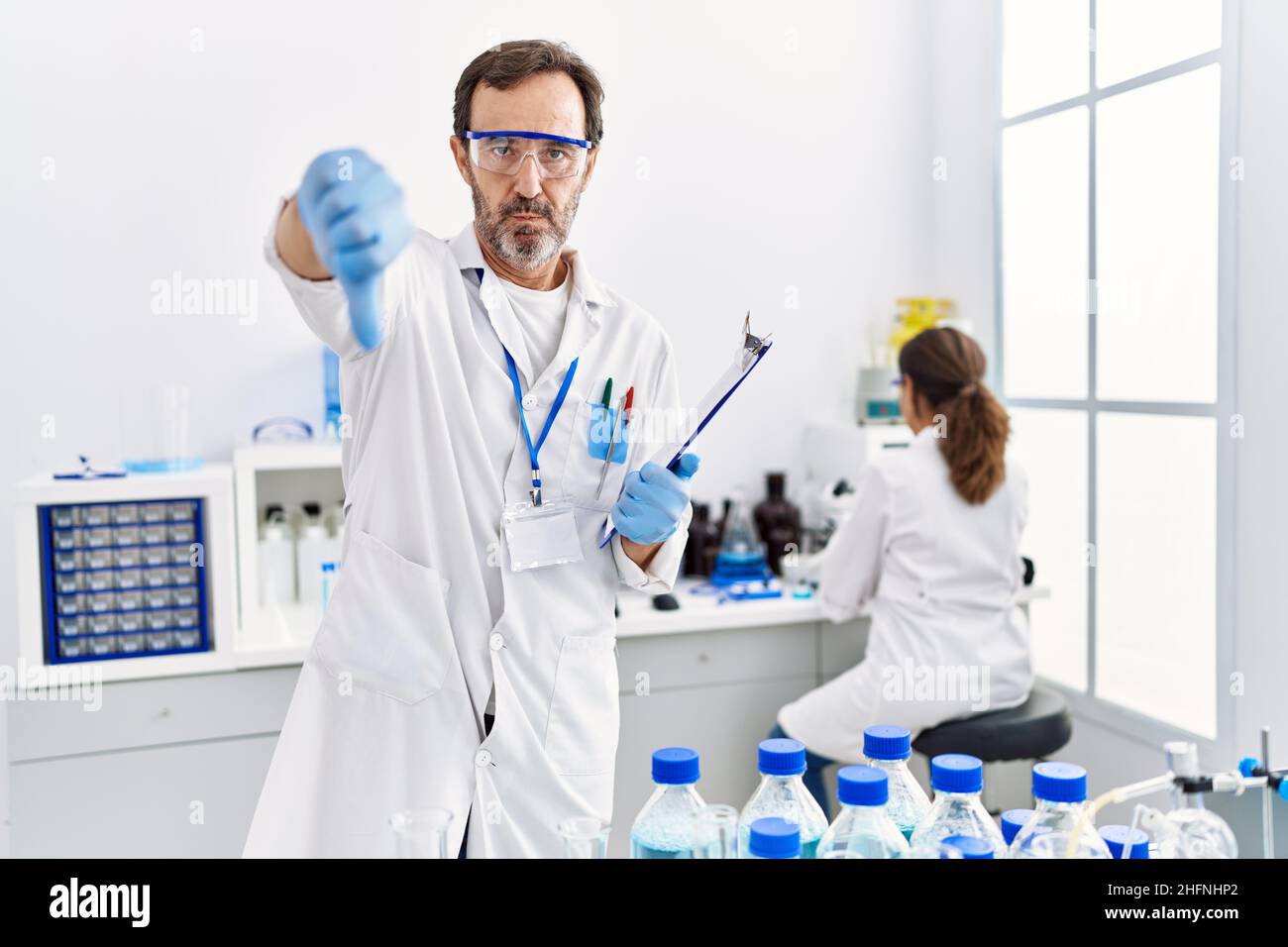 Middle age man working at scientist laboratory with angry face ...