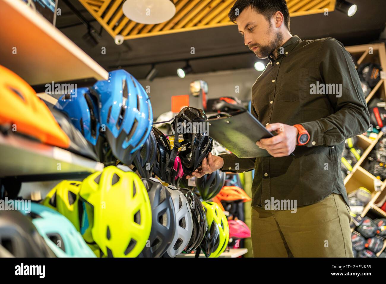 A male bike shop manager makes an inventory of sports helmets in a bike ...