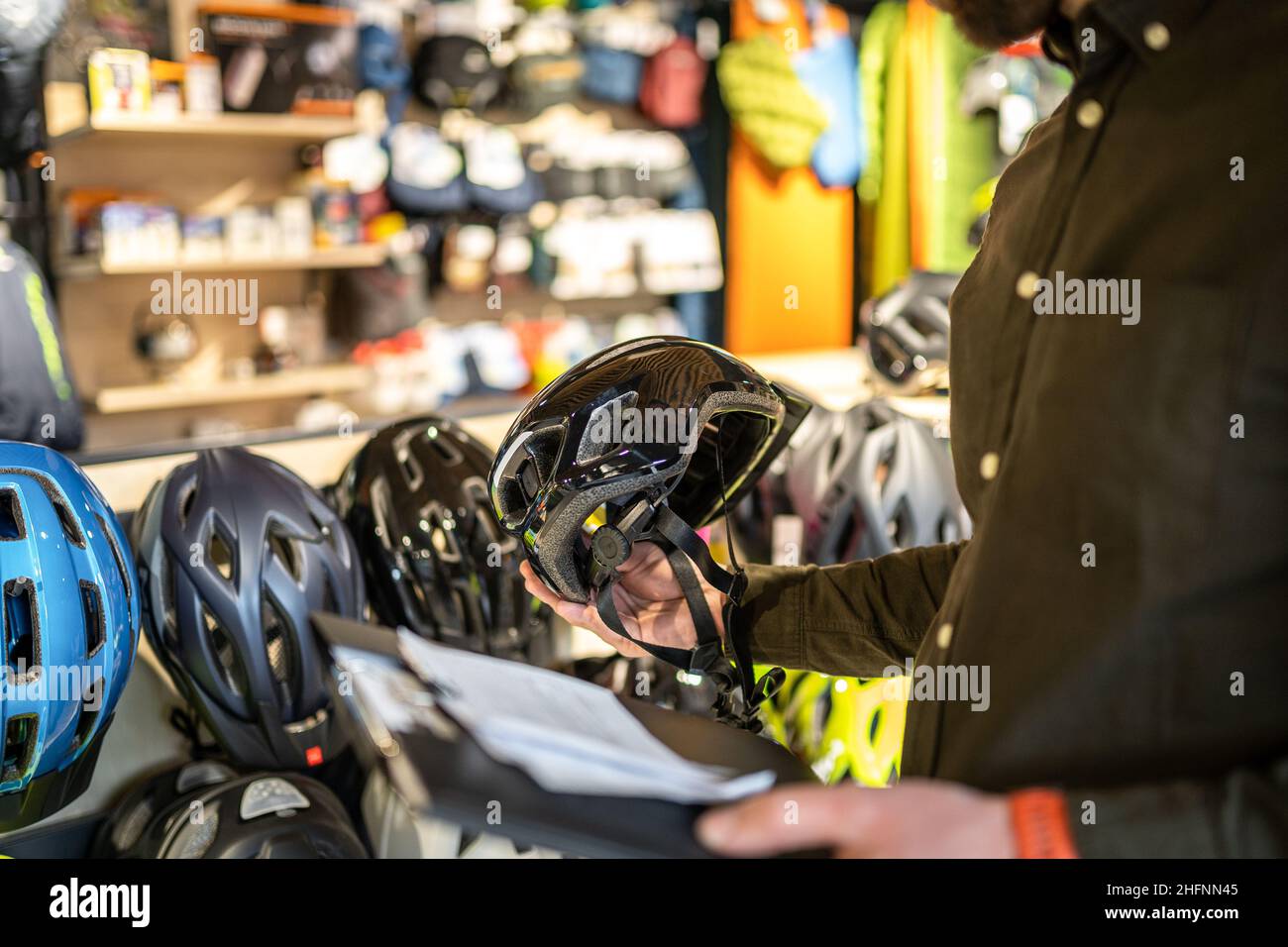 A male bike shop manager makes an inventory of sports helmets in a bike ...