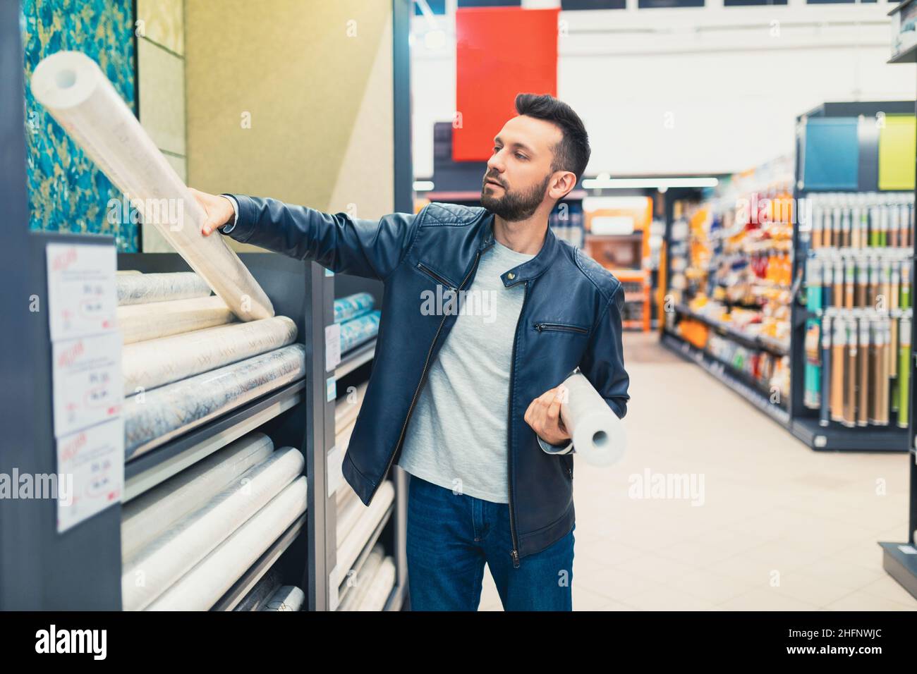 a customer in a hardware store chooses paper wallpaper for the walls ...
