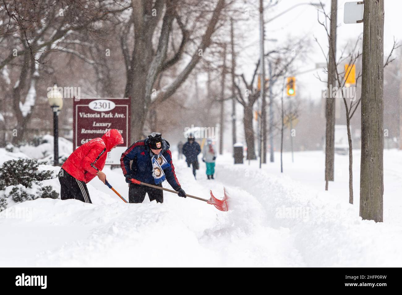Two young men shovel snow from an apartment building in Victoria Park ...
