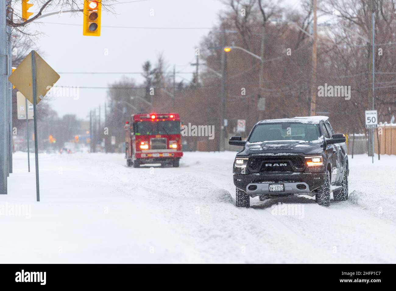 A RAM vehicle turns in front of a fire truck which is blaring its siren ...