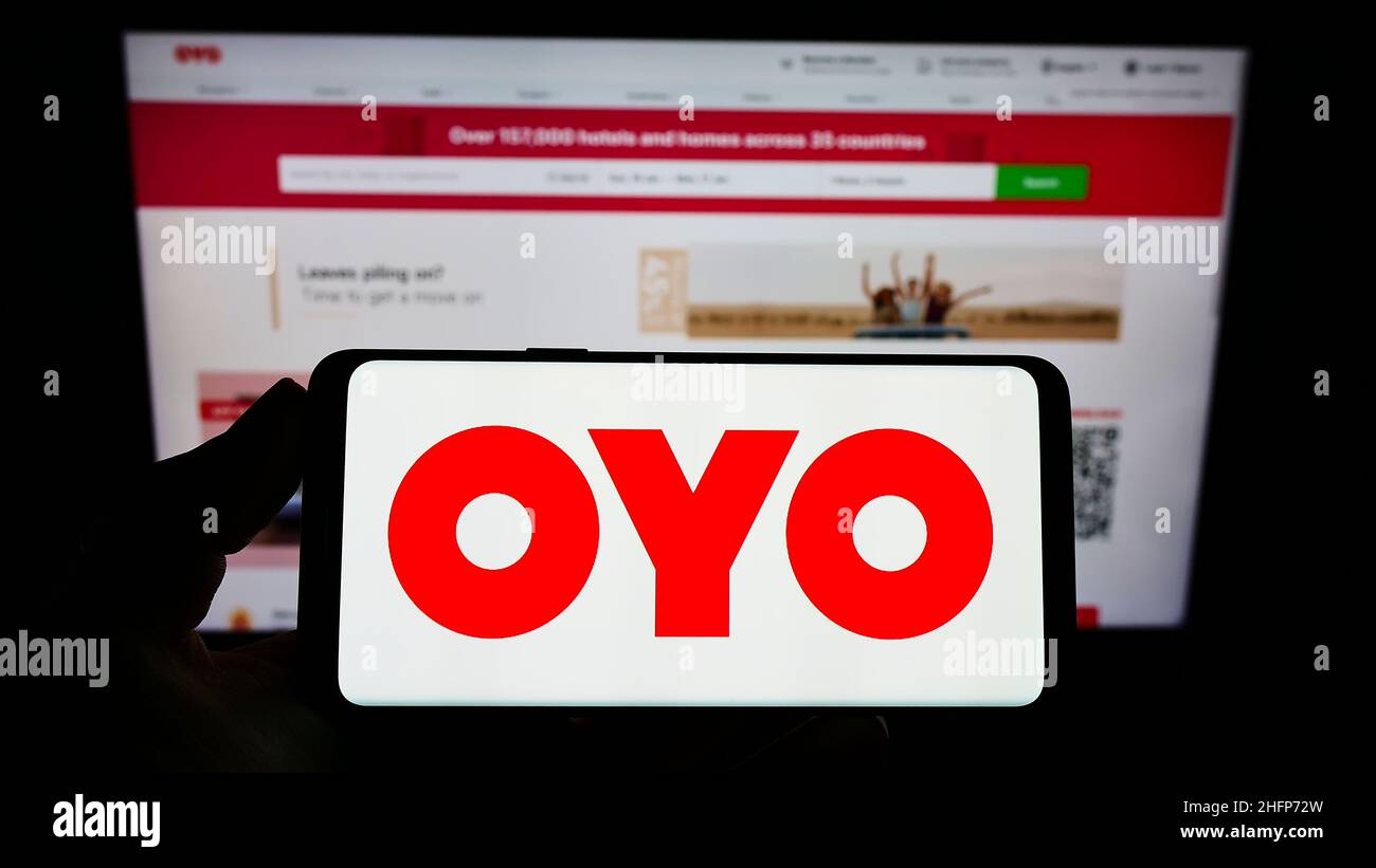 Person holding smartphone with logo of company Oravel Stays Private Limited (OYO Rooms) on ...