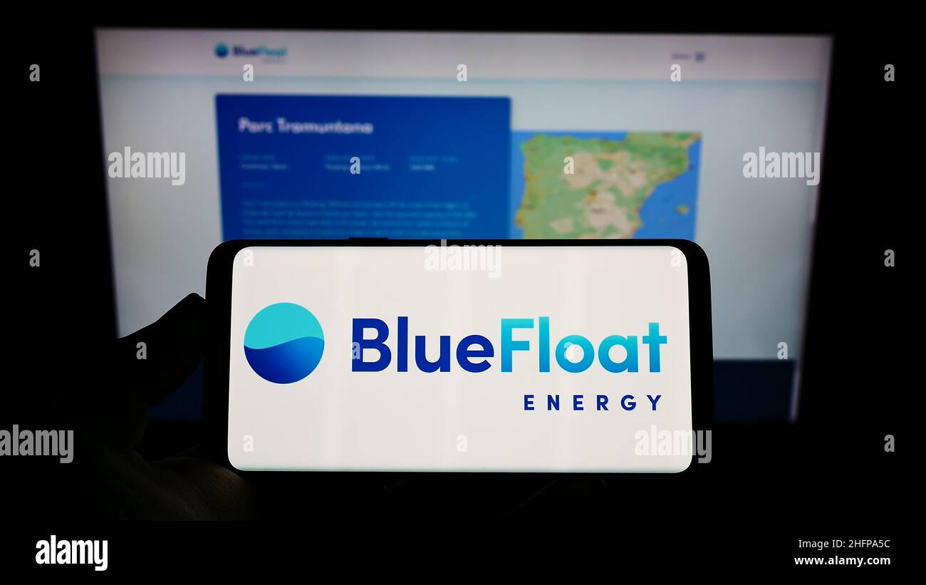 Person holding mobile phone with logo of Spanish renewables company ...