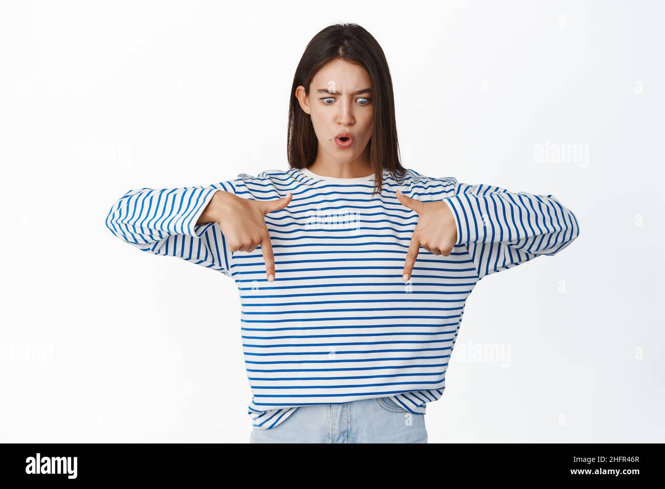 Wow whats that. Shocked young woman pointing and staring down with ...