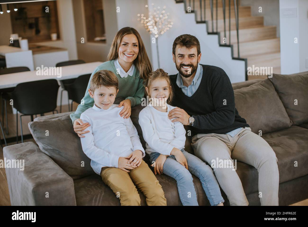 Happy young family with two kids enjoy time together on couch in living ...