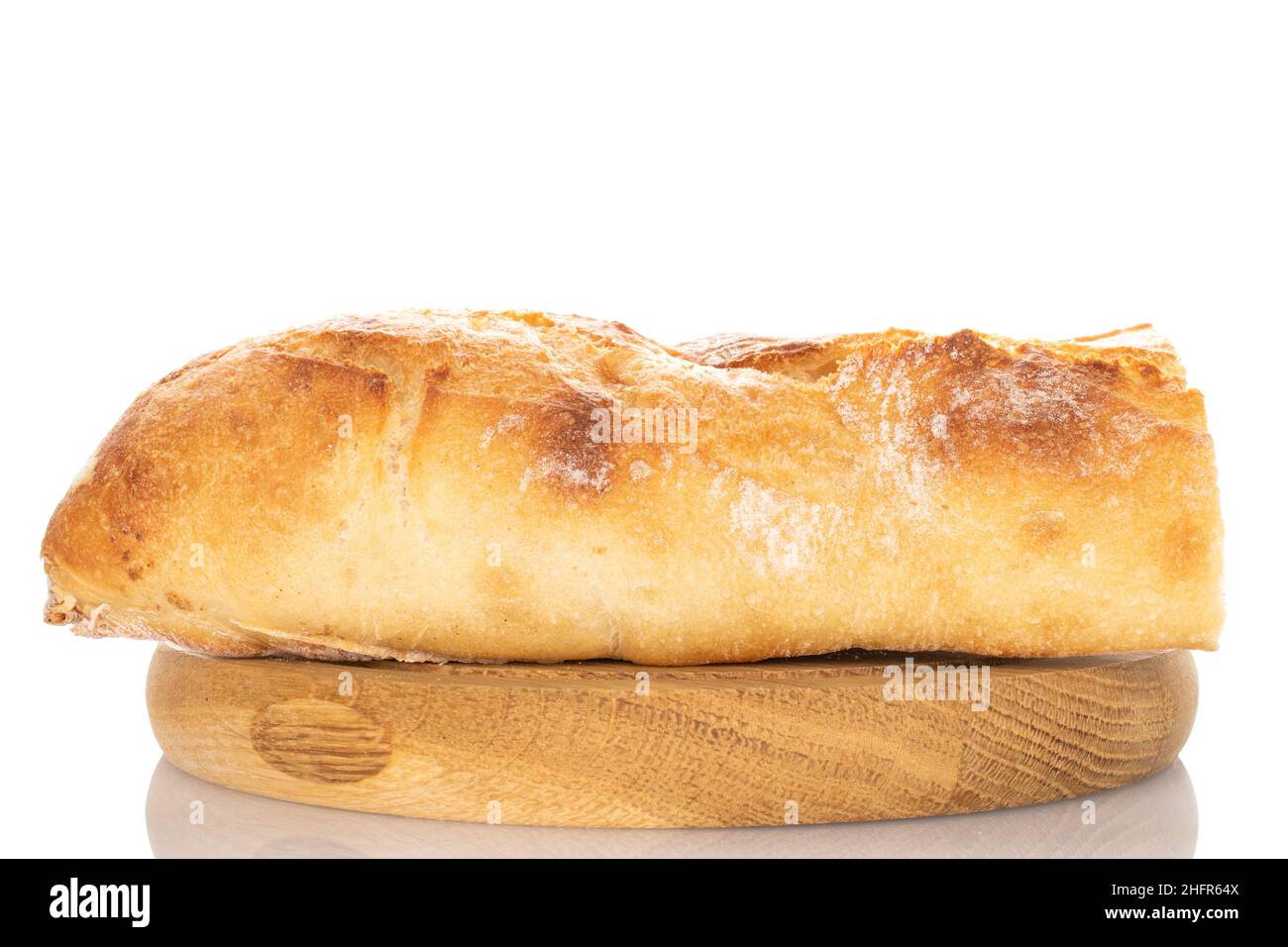 One half of delicious freshly baked French baguette on a round wooden ...