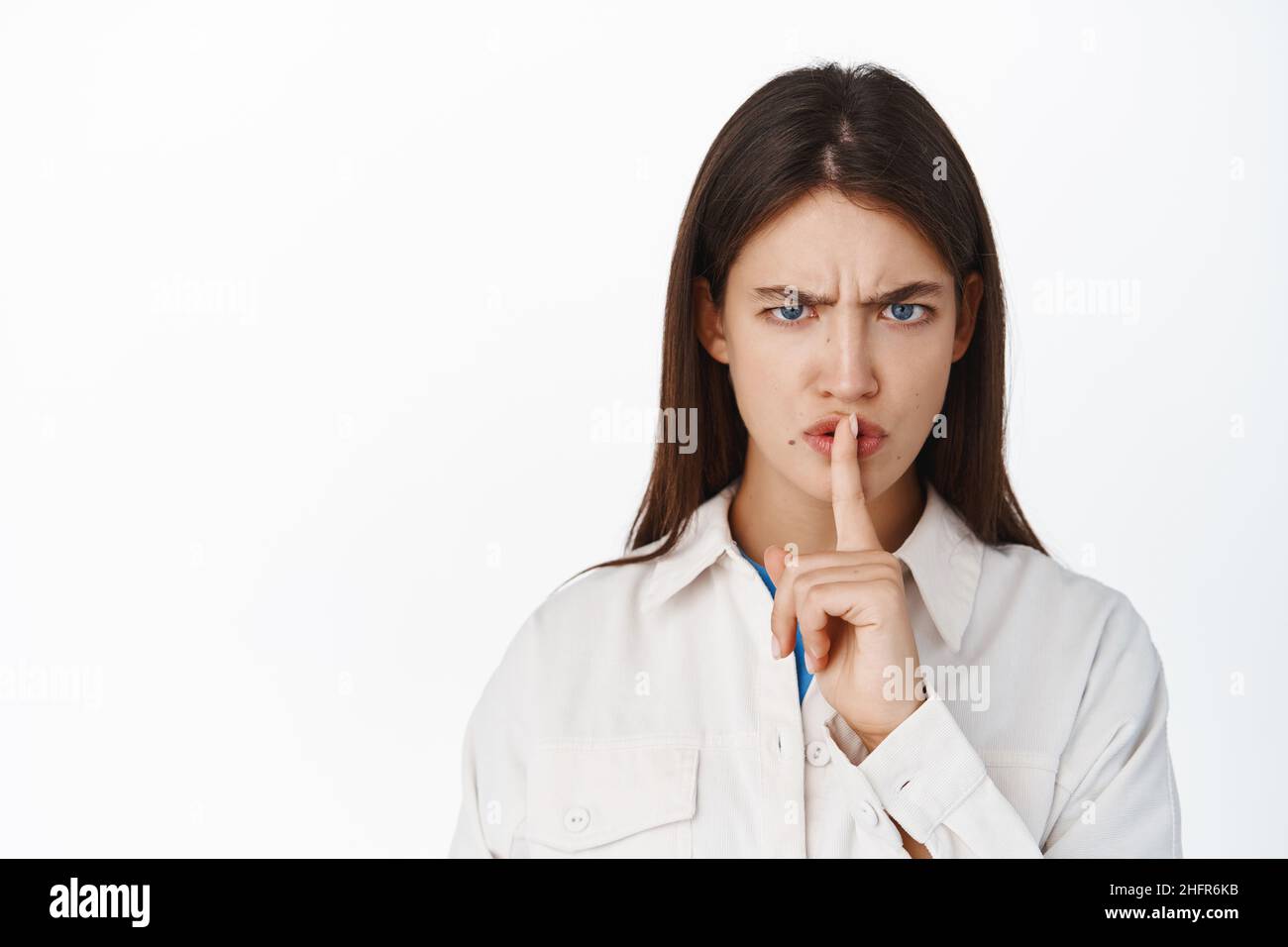 Young angry brunette woman hushing, making shh silence, be quiet ...