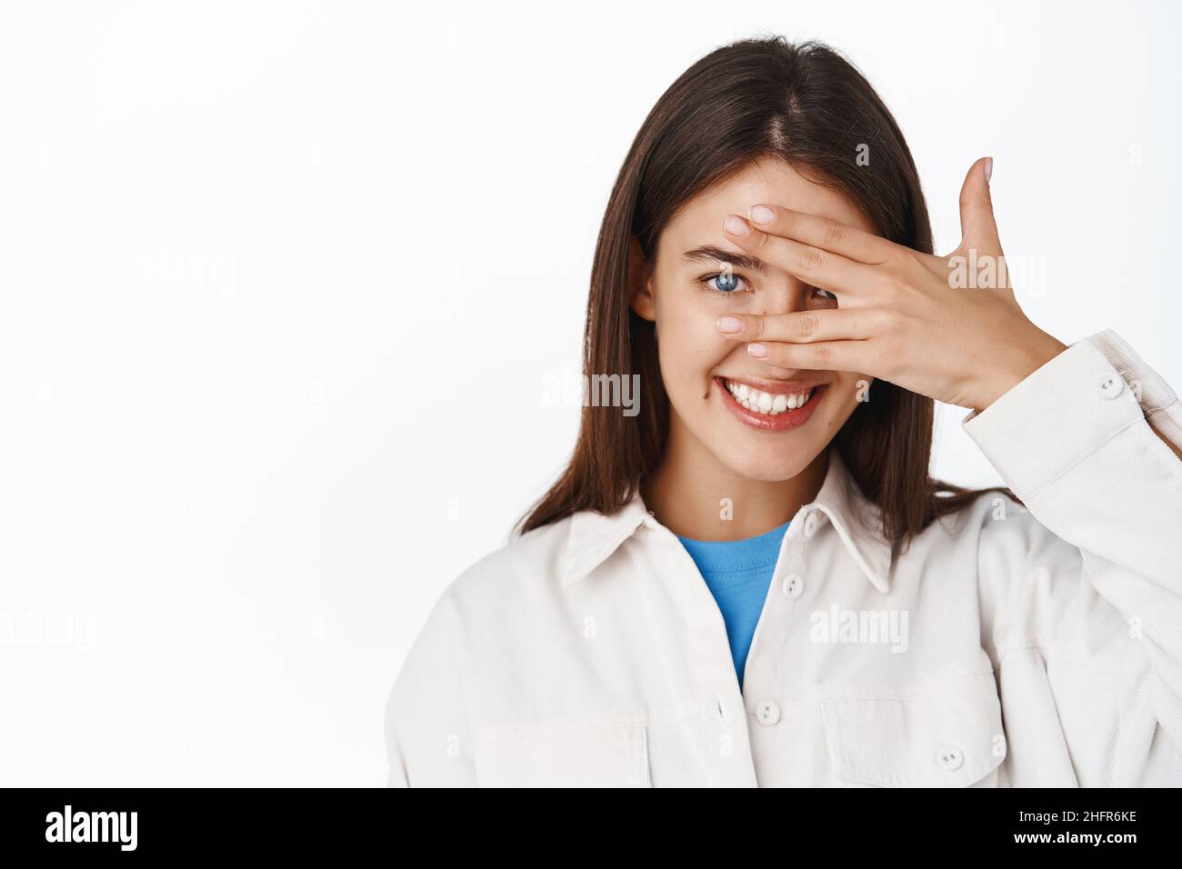 Close up portrait of cute young woman open fingers, looking through ...