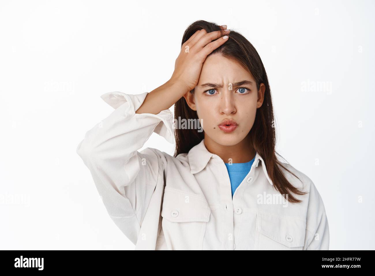 Close up of troubled girl holding hand on head, exhaling and frowning ...