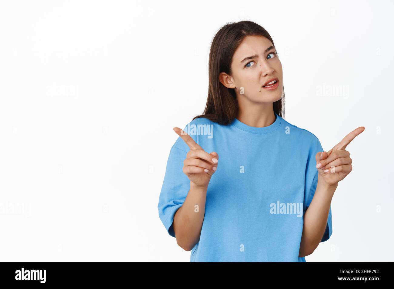 Portrait of indecisive college girl pointing sideways, picking between ...