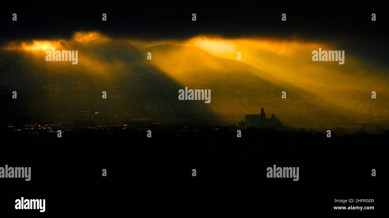 Sunbeams from sunlight streaming down brightly on a town with mountains ...