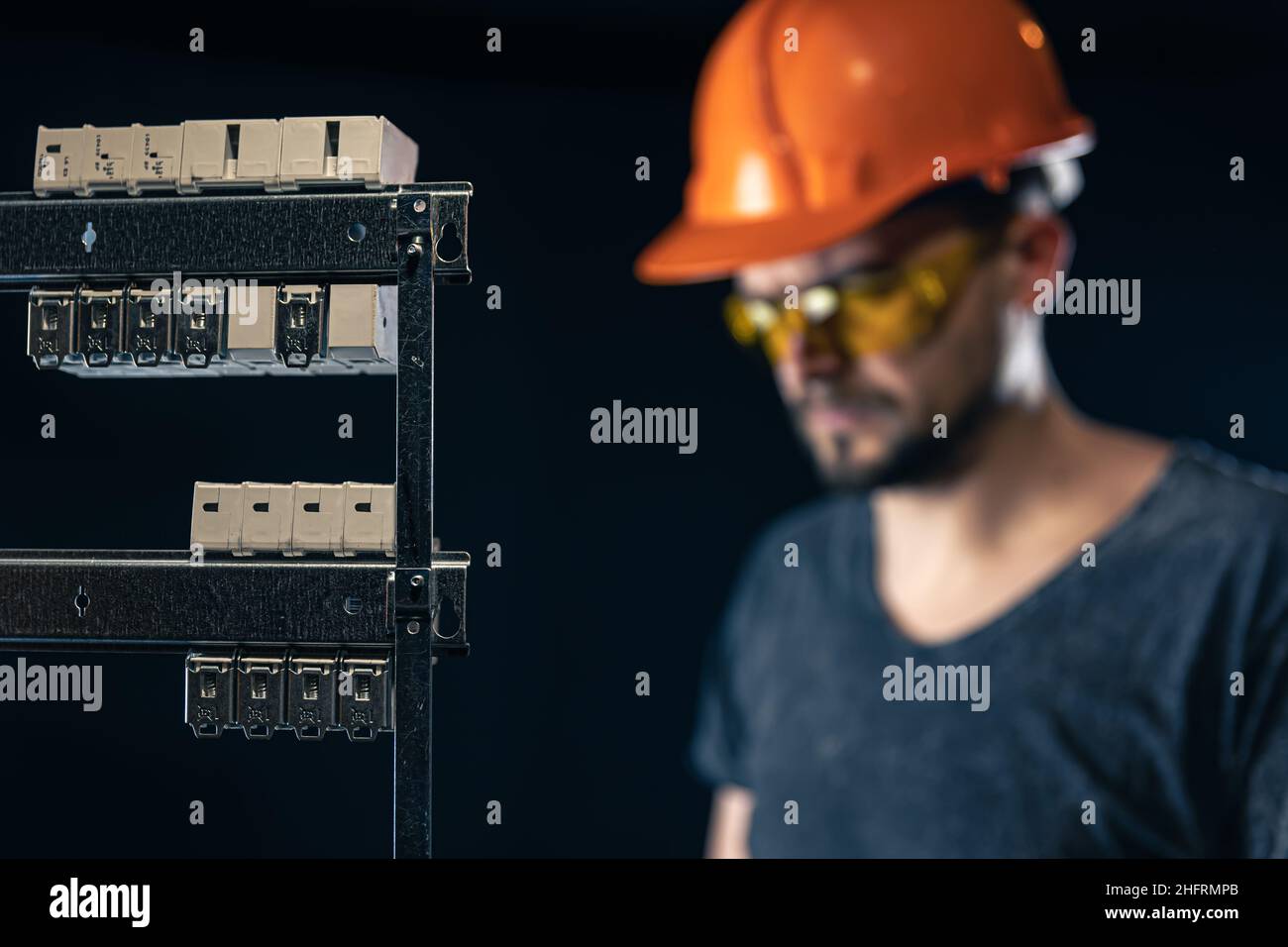 A male electrician works in a switchboard with an electrical connecting ...