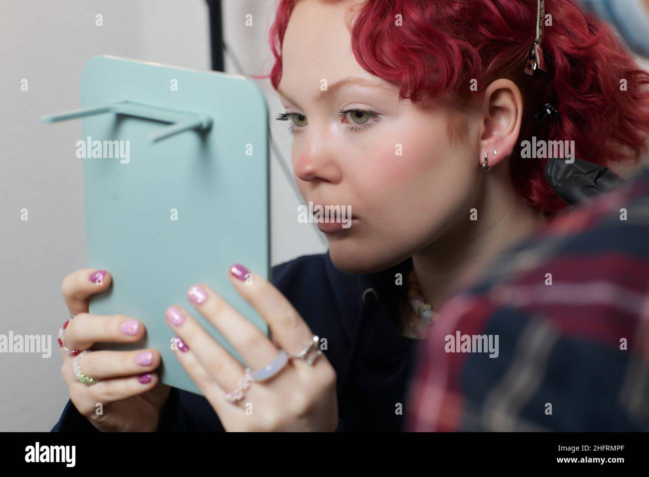 A beautician makes a puncture of the earlobe with a disposable device ...