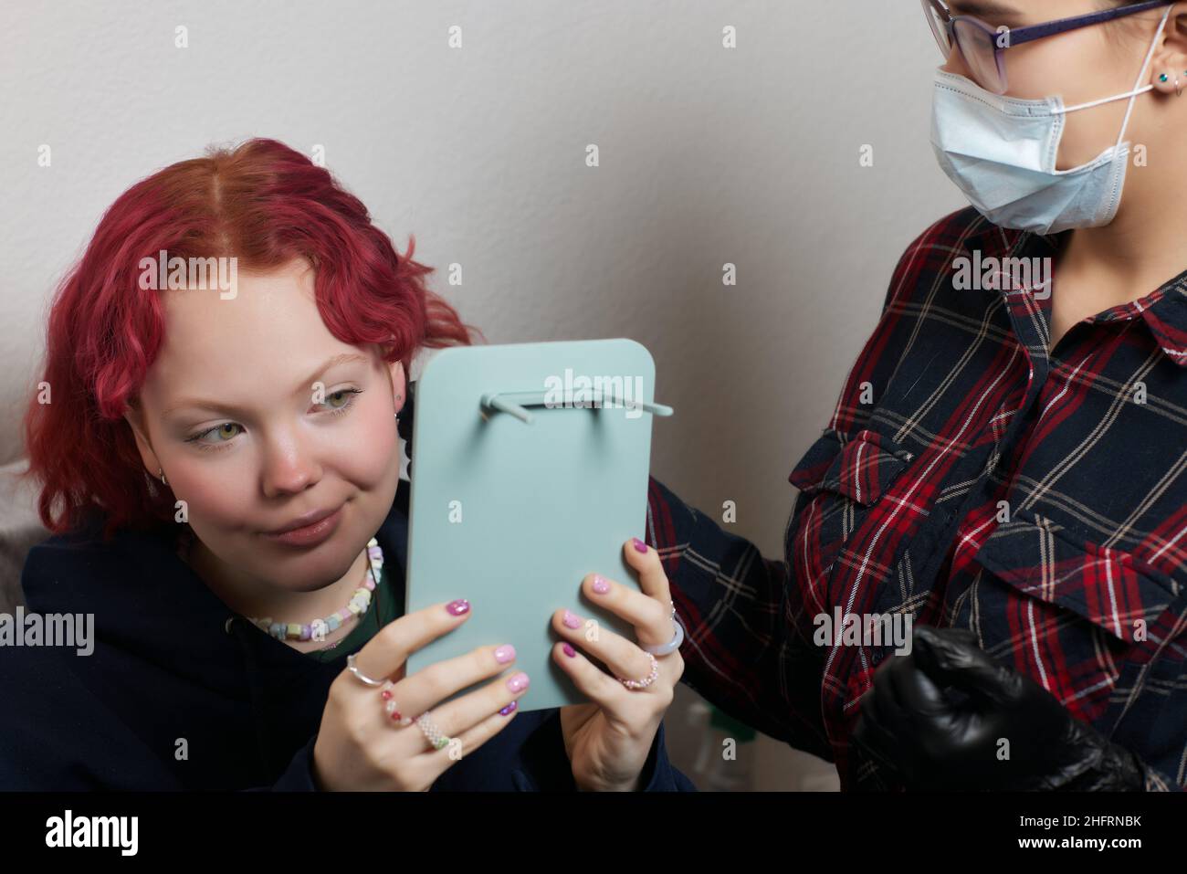 A beautician makes a puncture of the earlobe with a disposable device ...