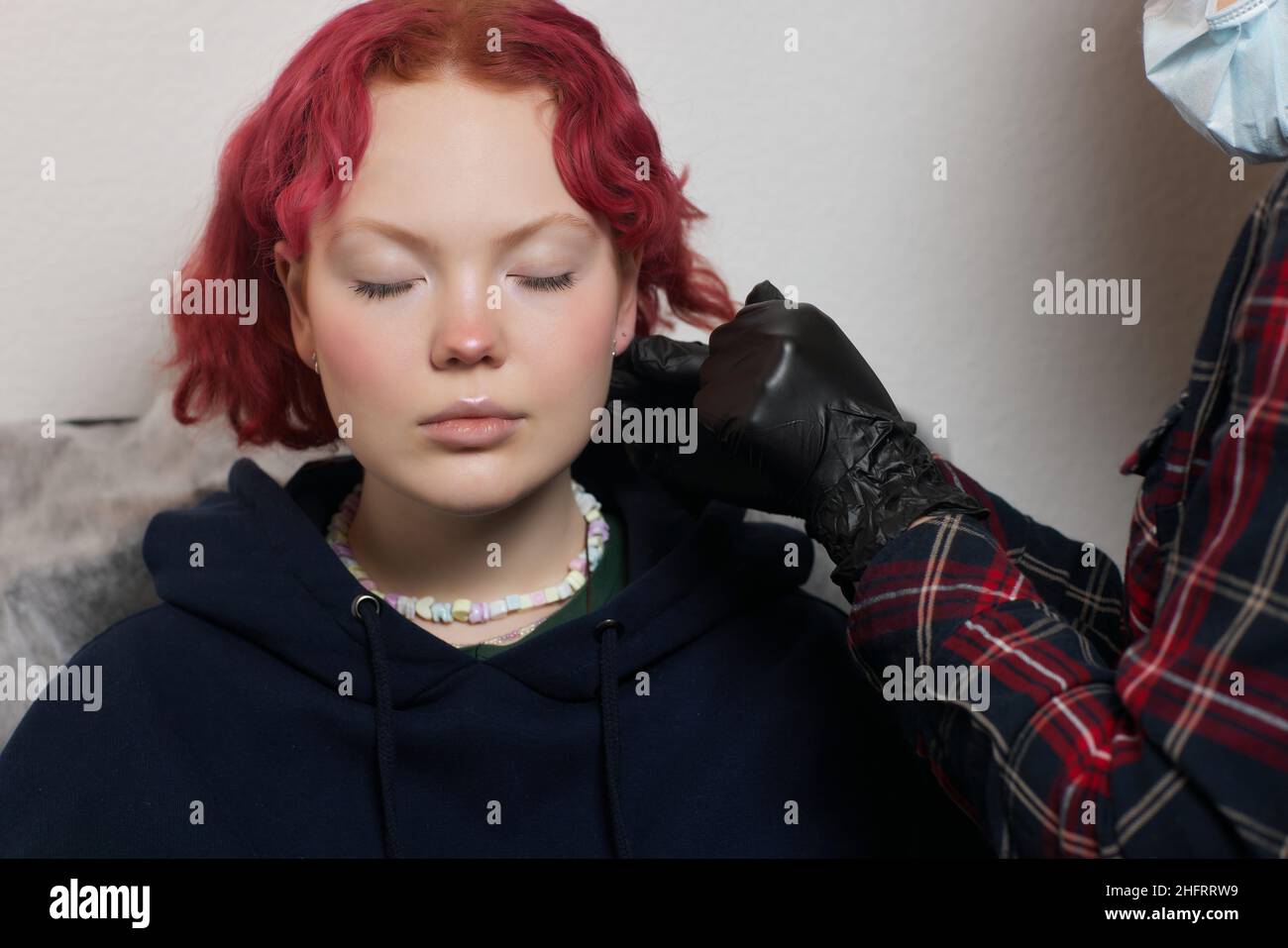 A beautician makes a puncture of the earlobe with a disposable device ...