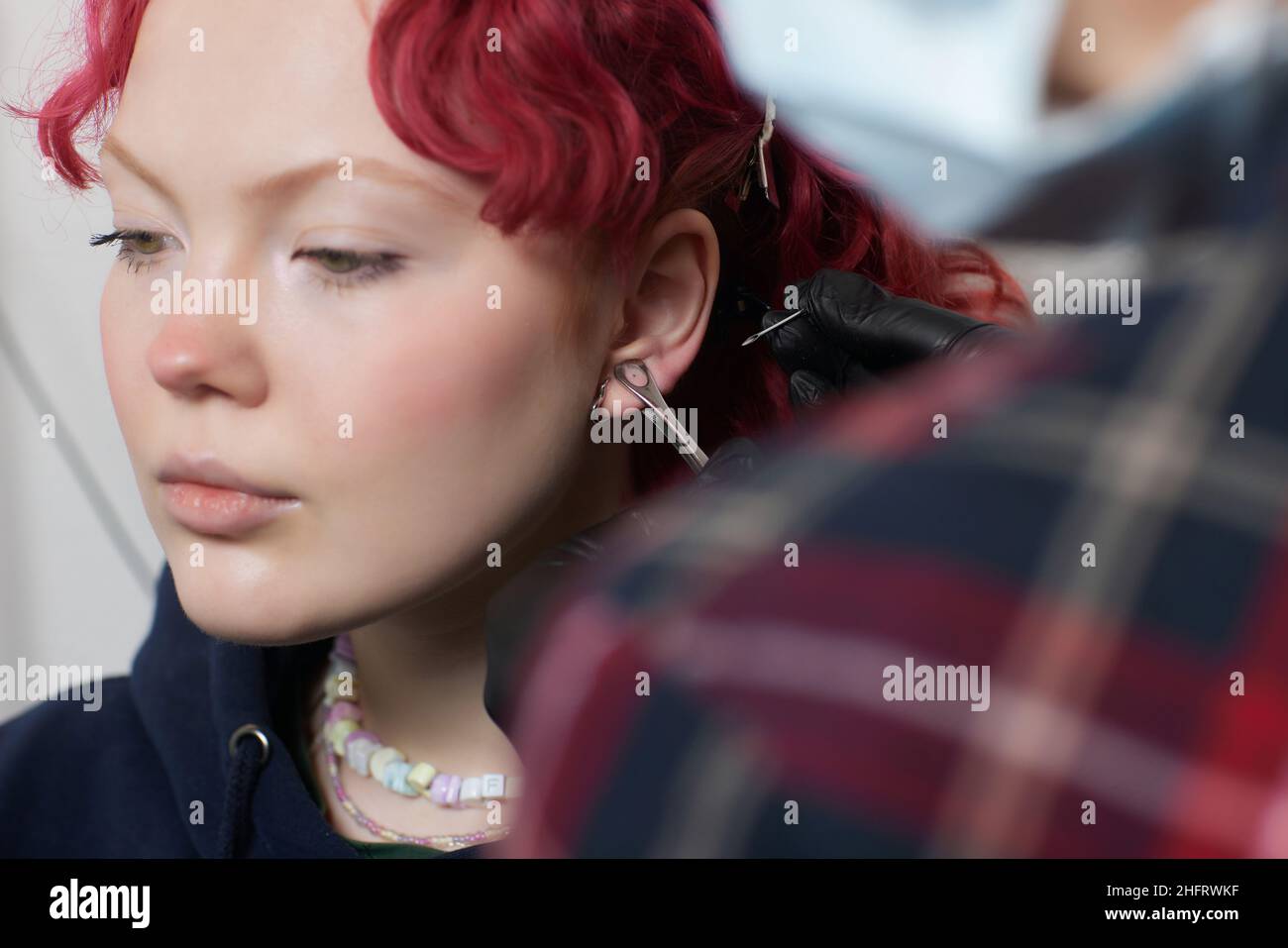 A beautician makes a puncture of the earlobe with a disposable device ...
