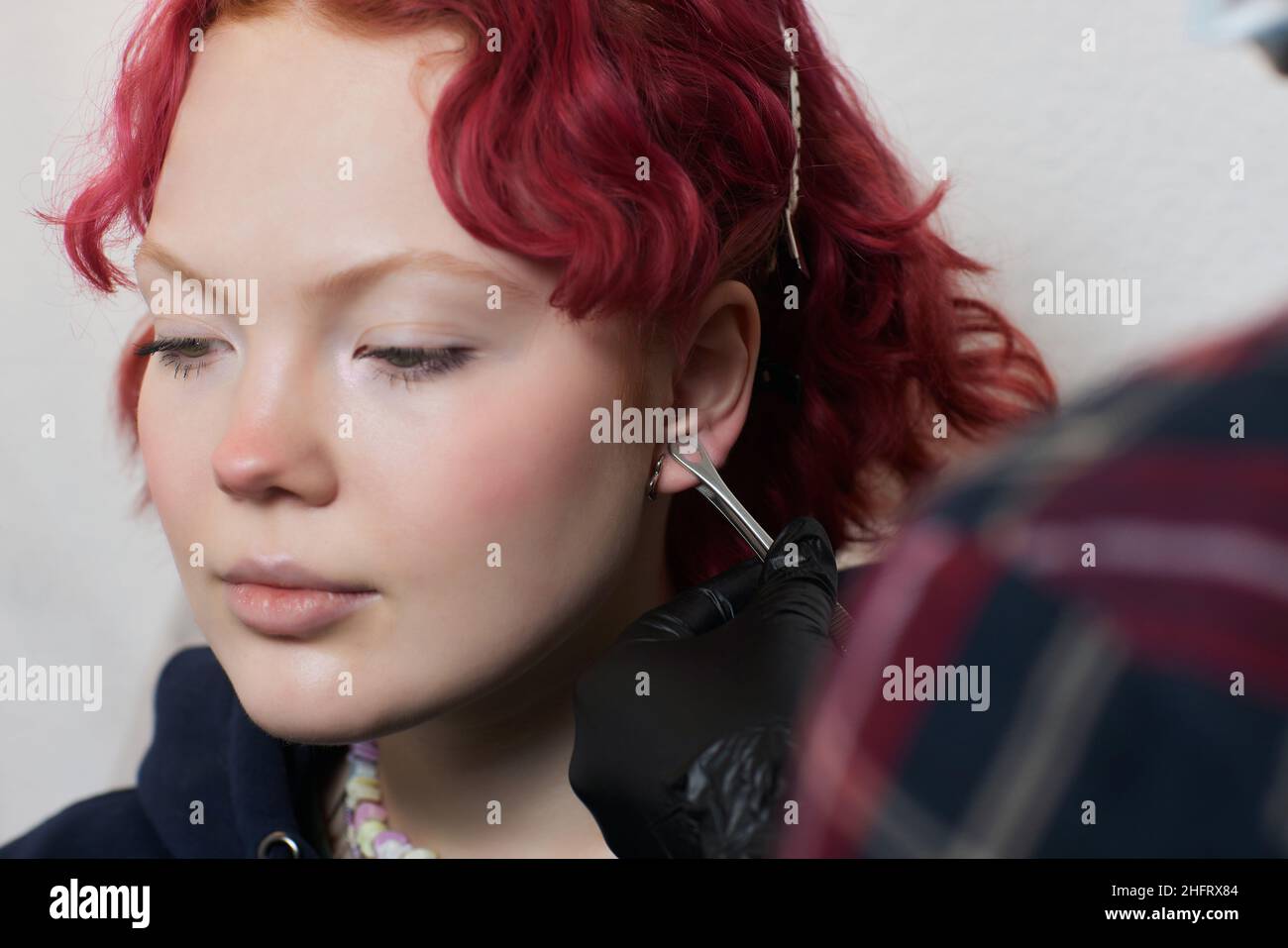 A beautician makes a puncture of the earlobe with a disposable device ...