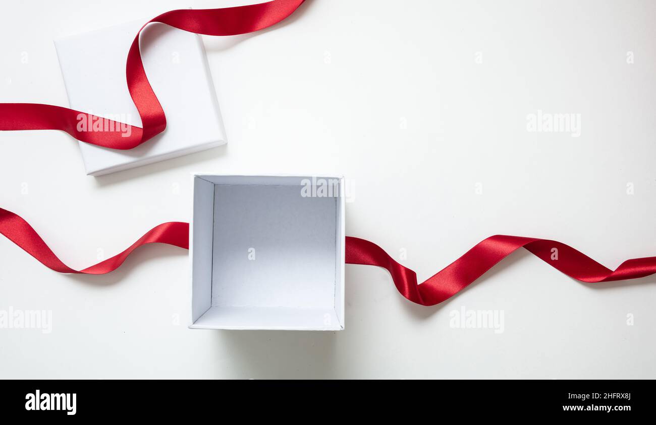 Overhead of open white box and red satin ribbon isolated on white ...