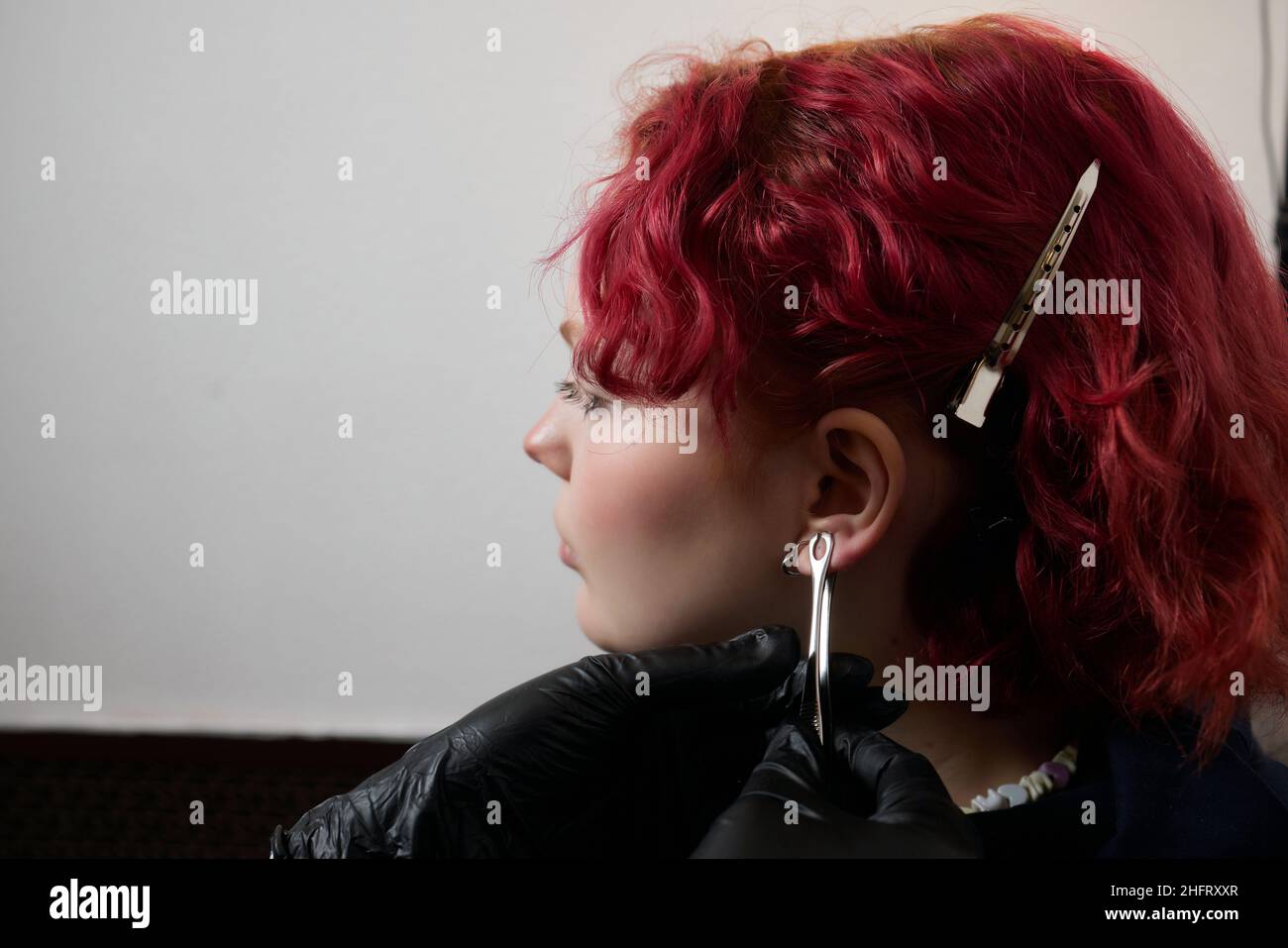 A beautician makes a puncture of the earlobe with a disposable device ...