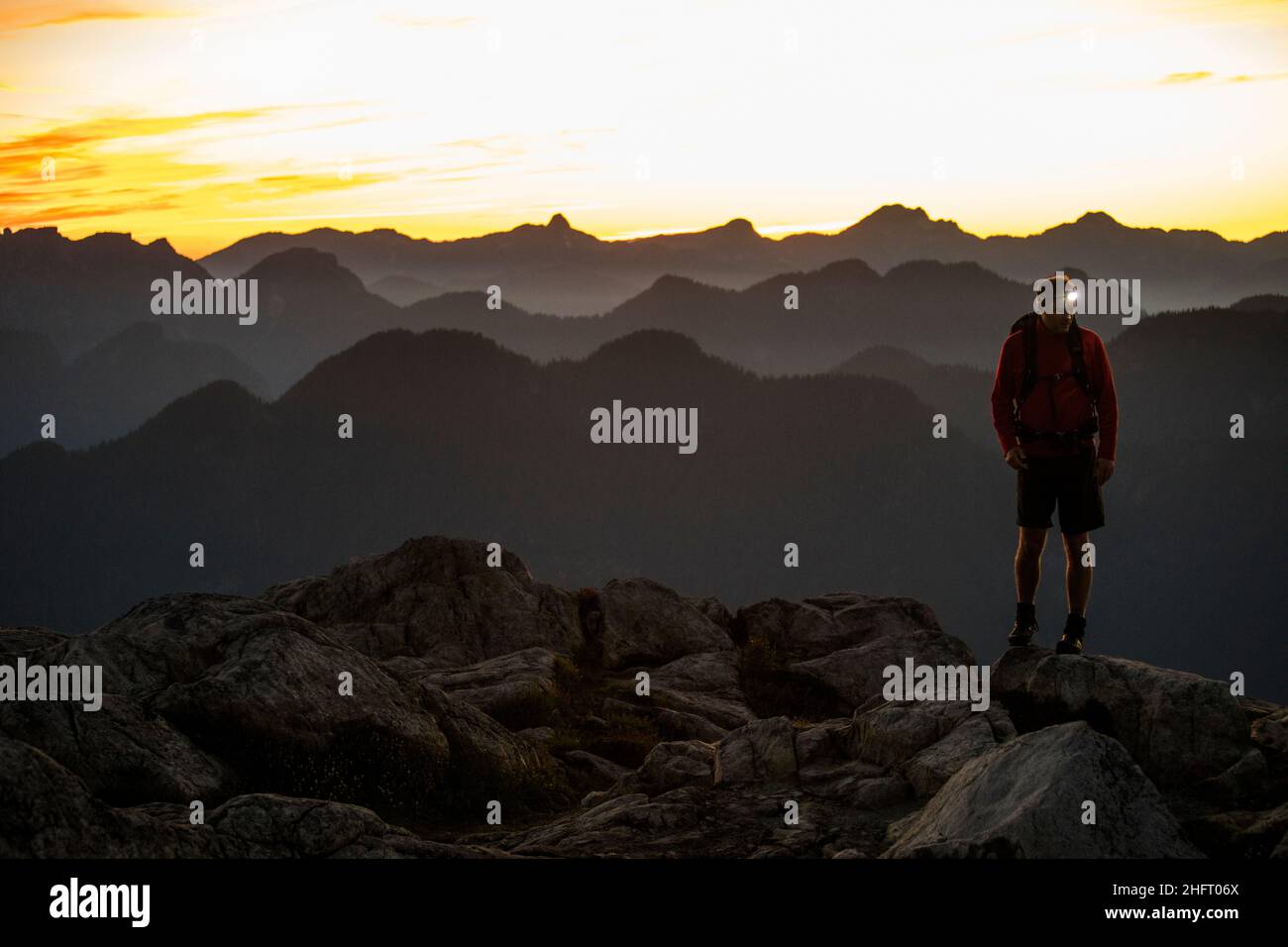 Mountaineer reaches summit at dawn, headlamp on Stock Photo - Alamy