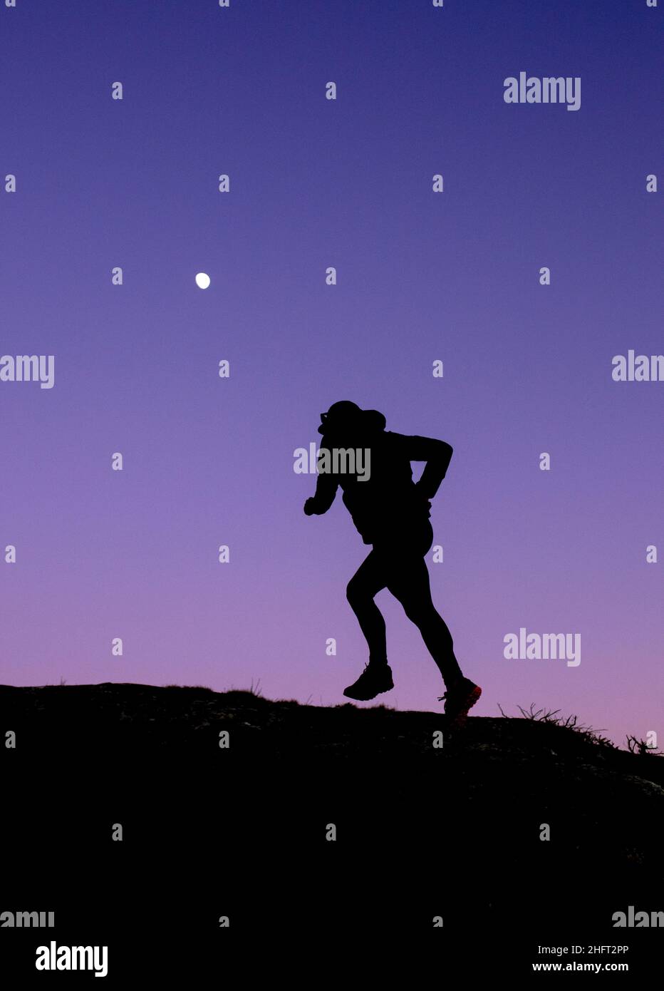 Trail runner silouhetted against purple sky at twilight with moon Stock ...