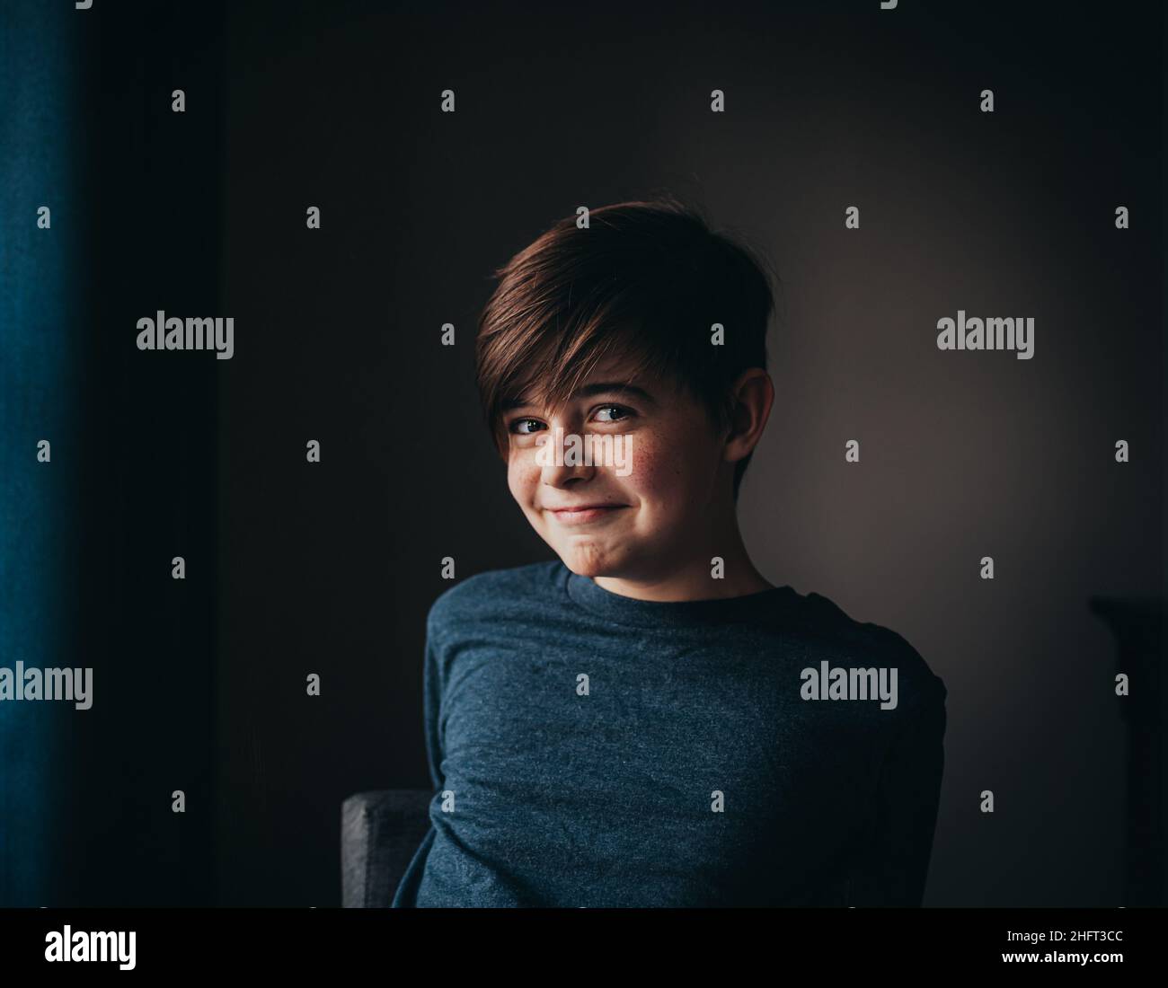 Portrait of happy tween boy in with smirk in a dark room Stock Photo ...