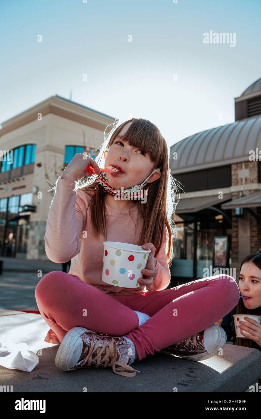 Young girl sitting on ledge eating ice cream Stock Photo - Alamy