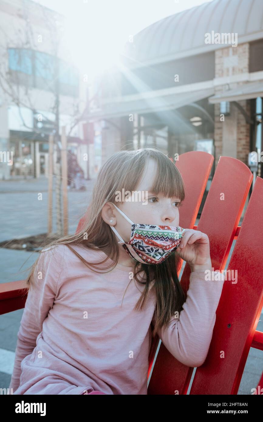 Young girl looking away and pulling down mask outside Stock Photo - Alamy
