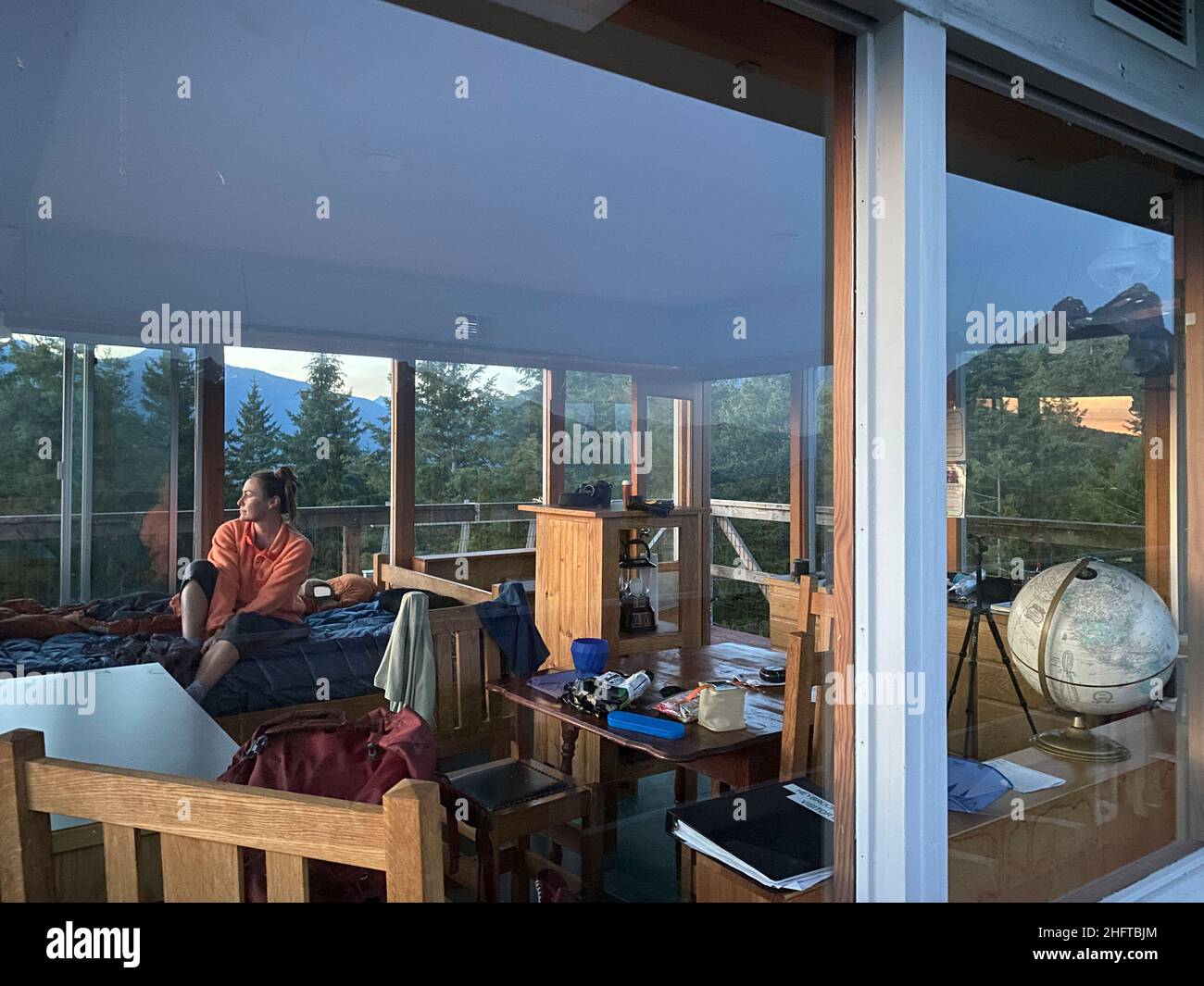 Female watching sunset from inside a fire lookout in the Cascades Stock ...