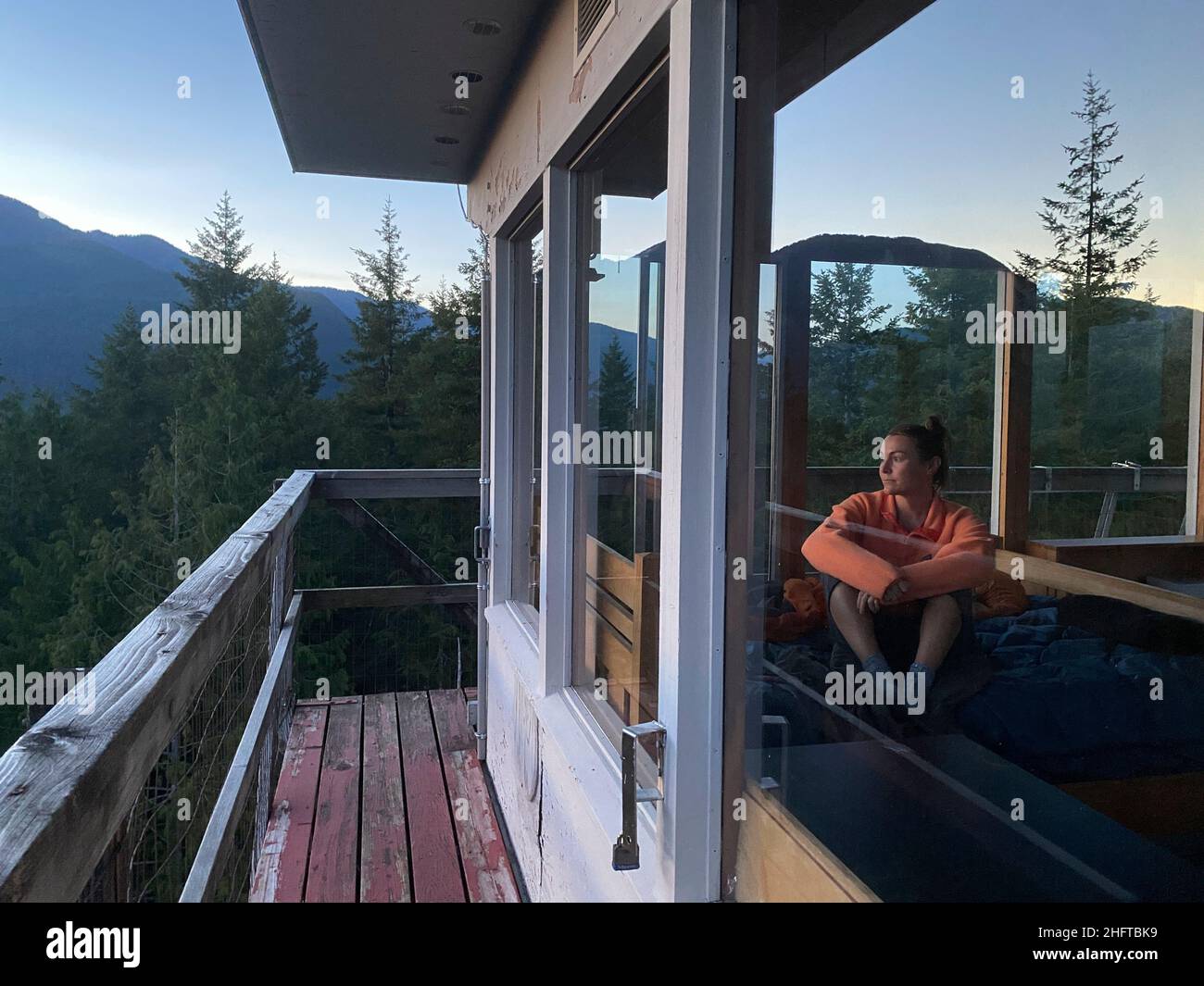 Female watching sunset inside a fire lookout in the mountains Stock ...
