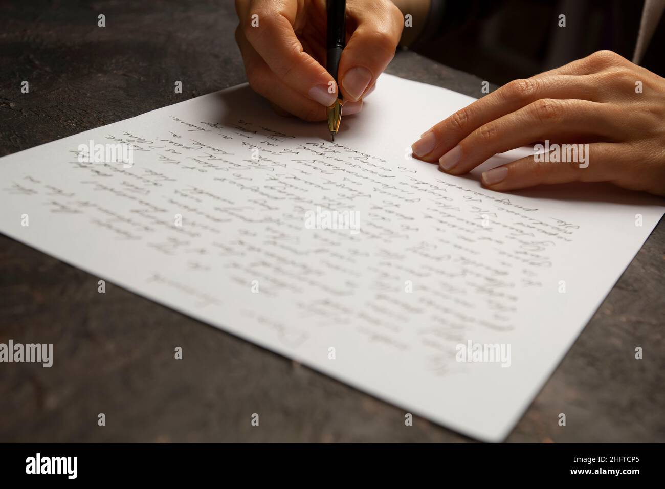 The woman writes a letter. Cropped hands on the table with pen and ...