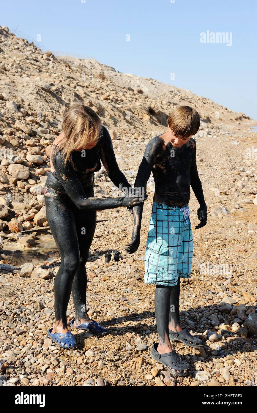 Woman daubed the boy therapeutic mud on the shore of the Dead Sea Stock ...