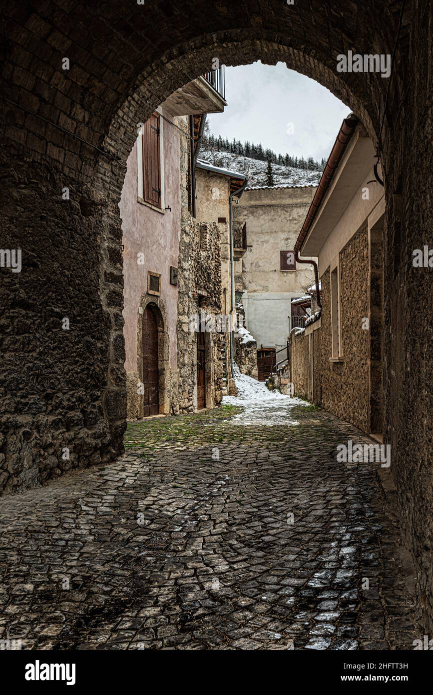 Access arch with cobbled floor with old houses with snow. Secinaro ...