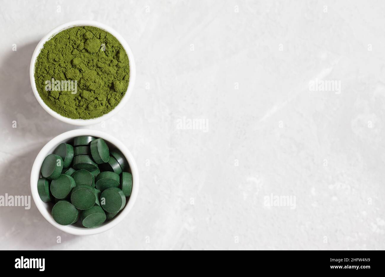 Chlorella and spirulina in bowls on a white concrete background ...