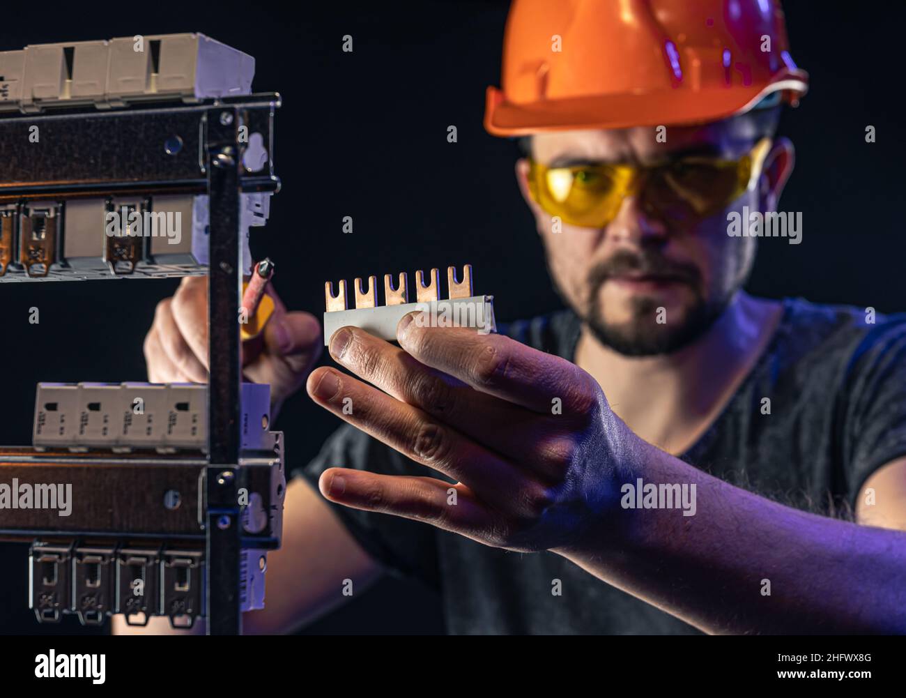 A male electrician works in a switchboard with an electrical connecting ...