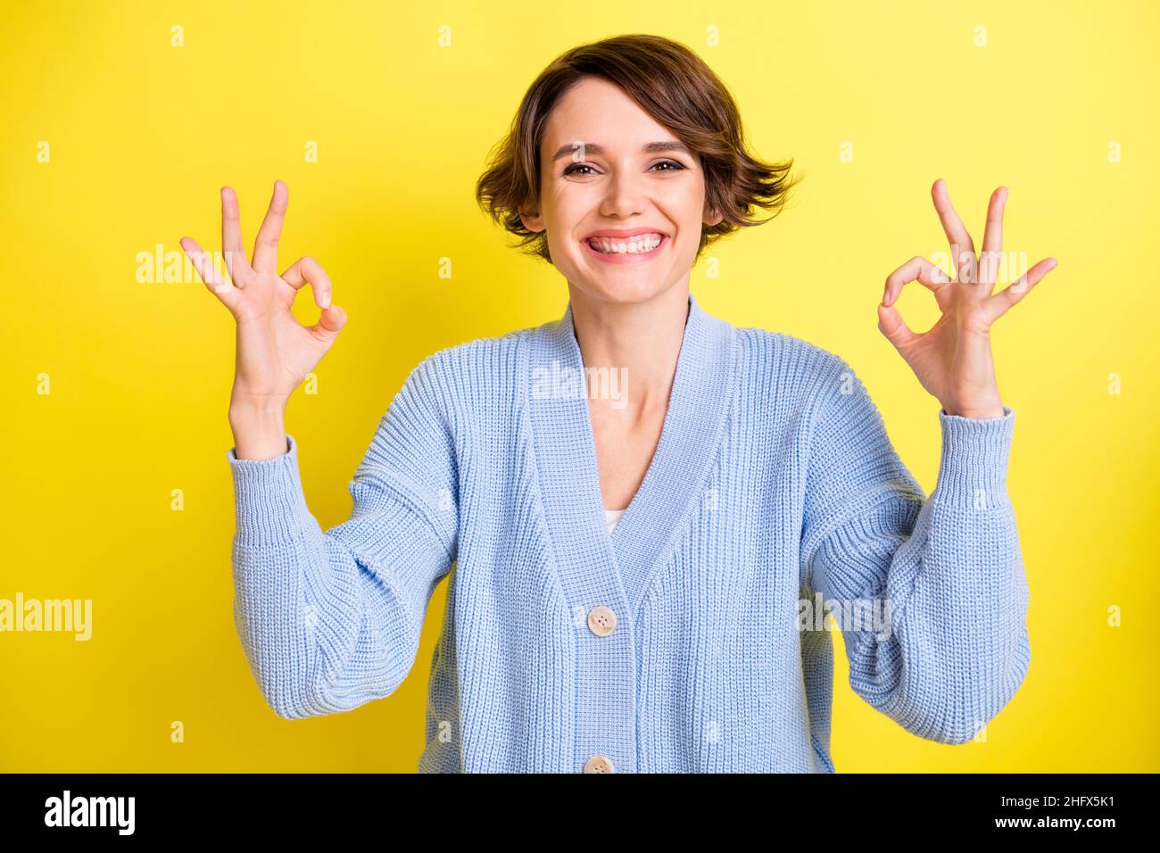 Portrait of attractive cheerful brown-haired girl showing double ok ...
