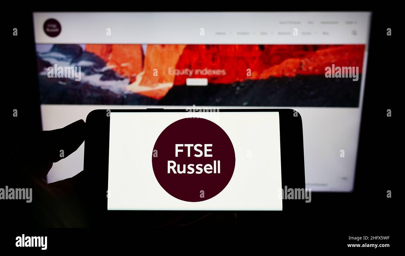 Person holding mobile phone with logo of British company FTSE Russell ...