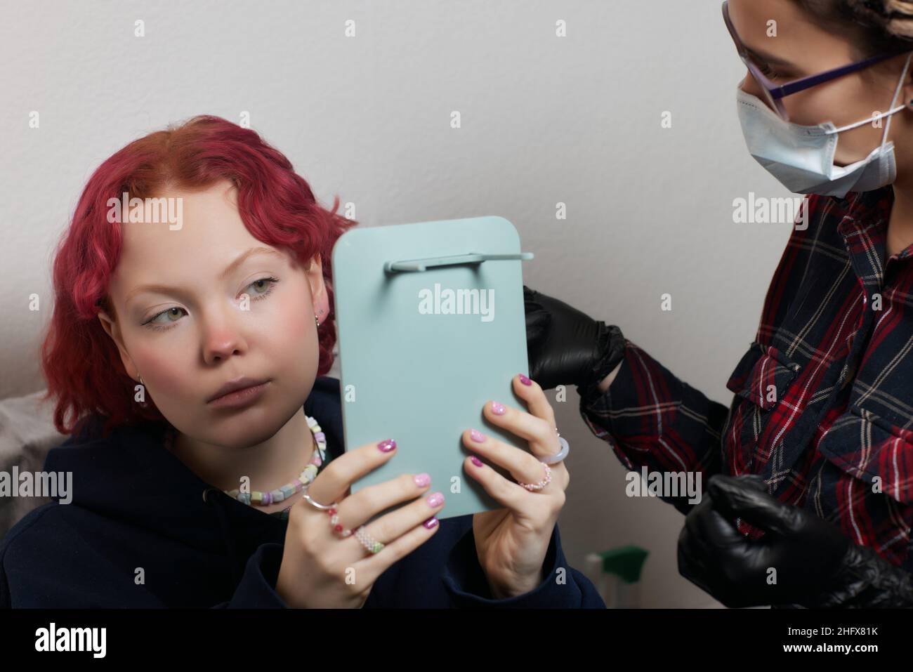 A beautician makes a puncture of the earlobe with a disposable device ...