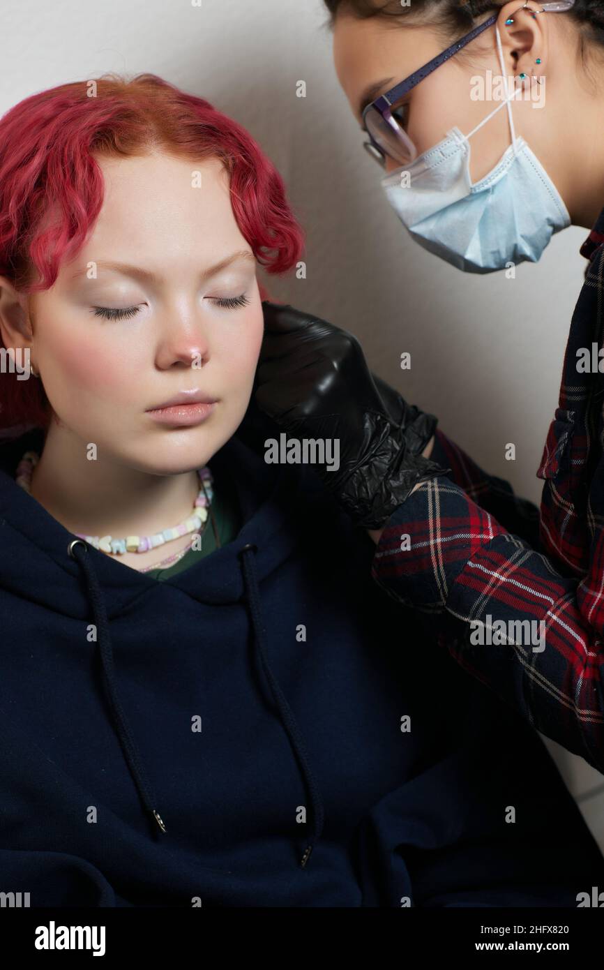 A beautician makes a puncture of the earlobe with a disposable device ...
