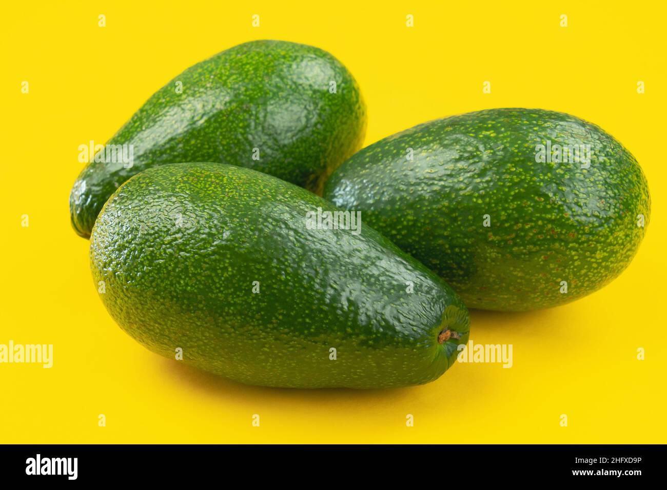 three avocados on a yellow background Stock Photo - Alamy
