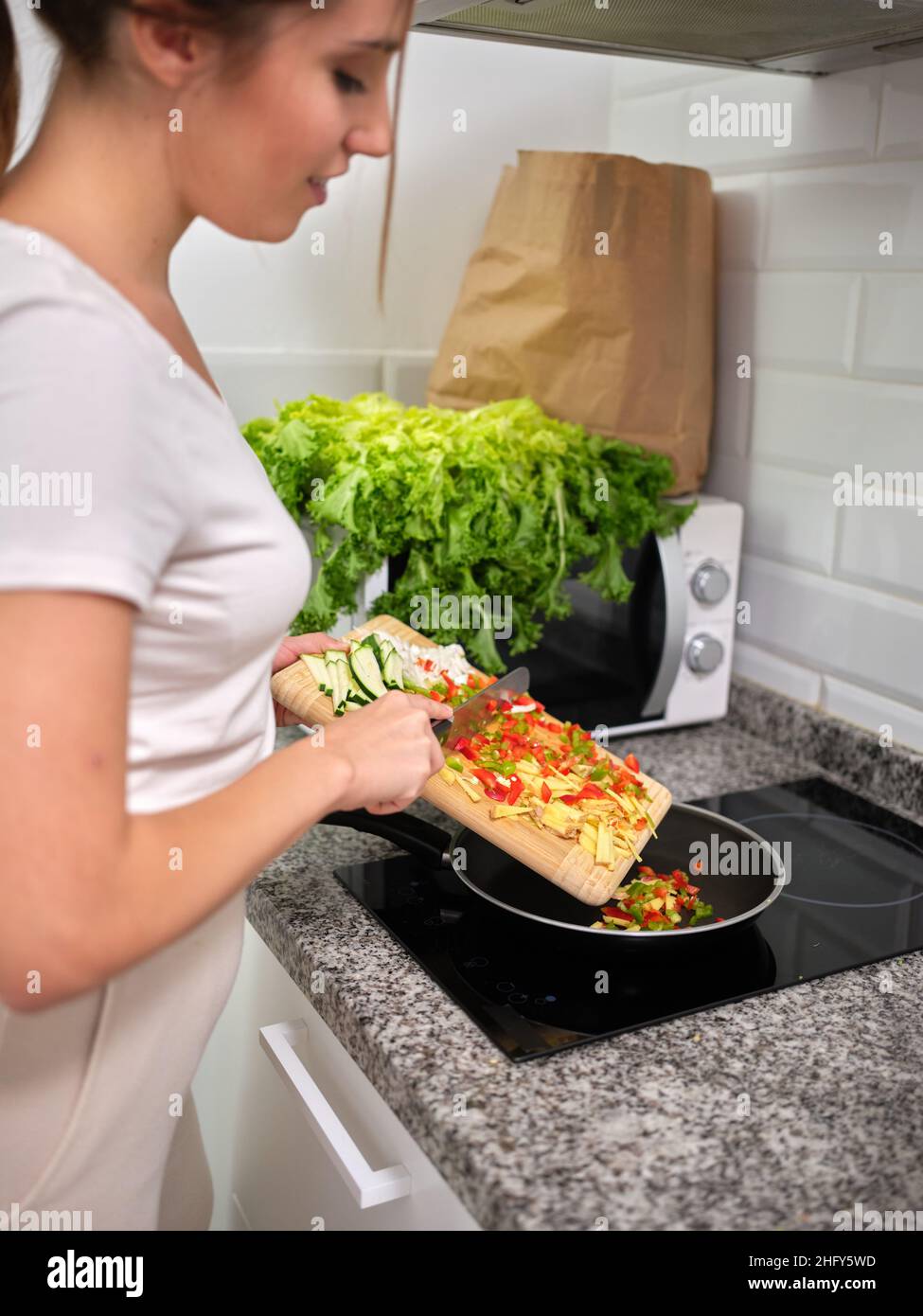 woman throwing the chopped vegetables into the pan to cook them Stock ...