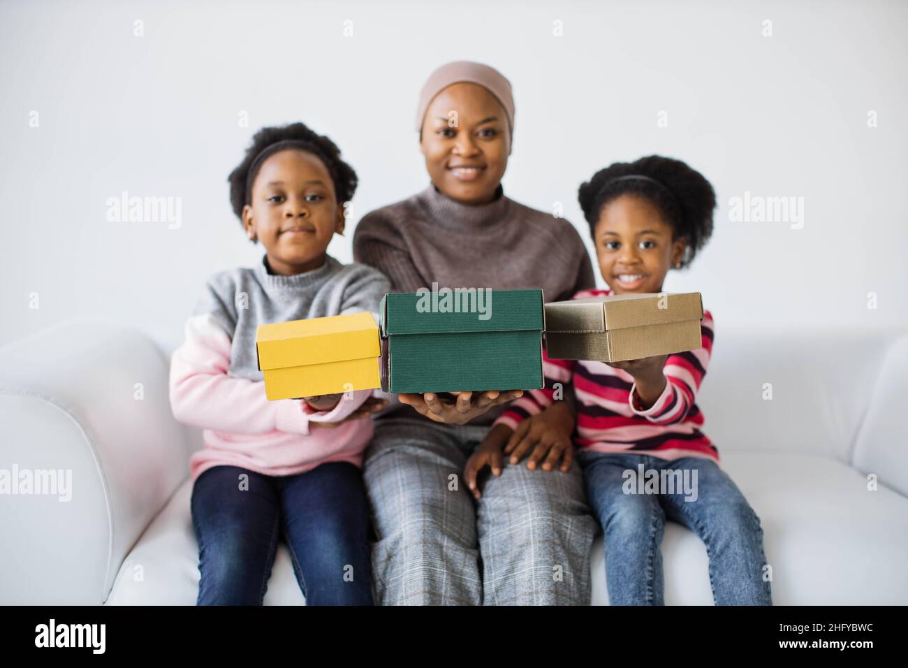 Happy african mother in headscarf and two cute daughters sitting on ...