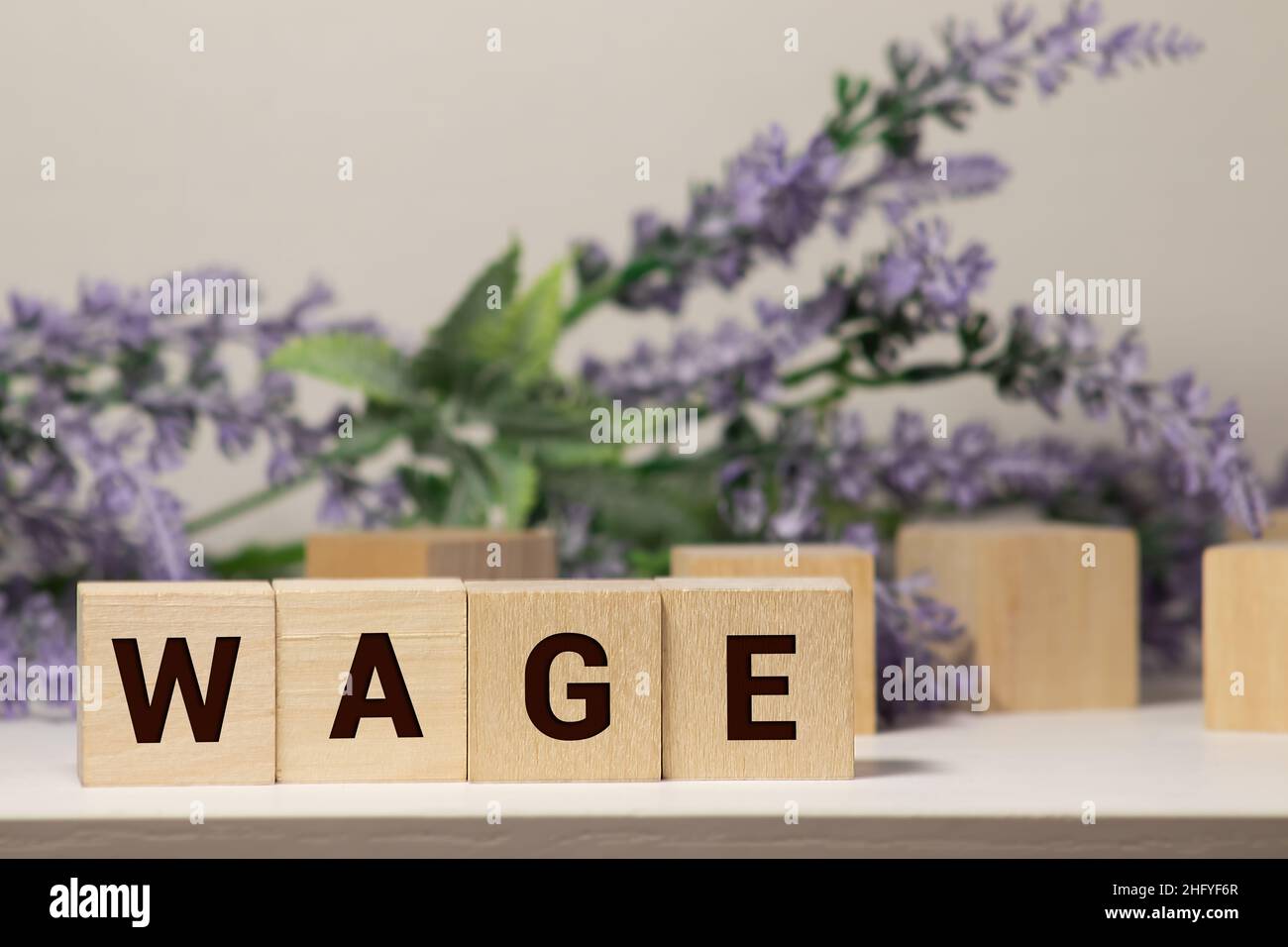 Person's Hand Protecting Wage Text On Wooden Blocks On Wooden Table ...
